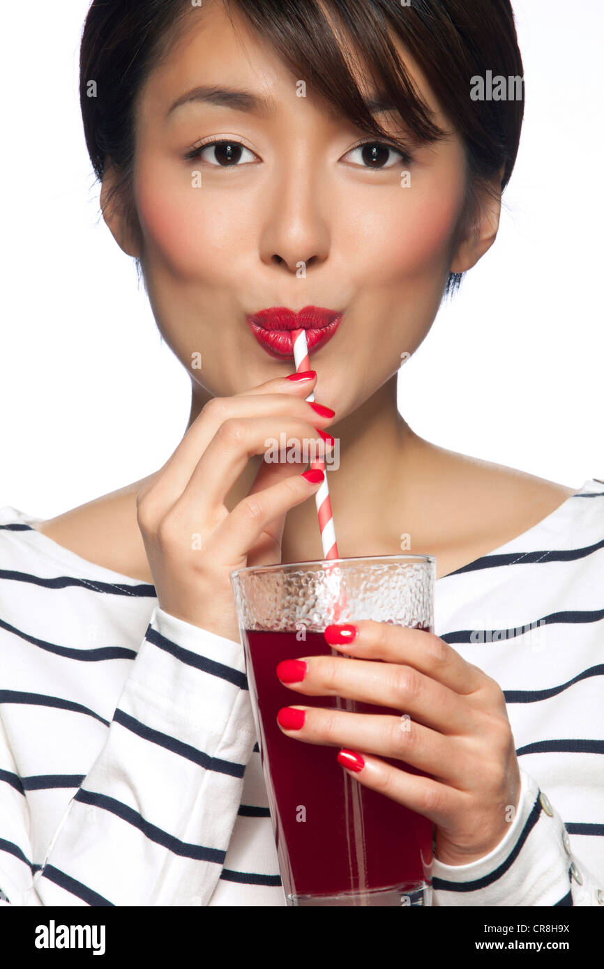 Young woman drinking from straw against white background Stock Photo ...
