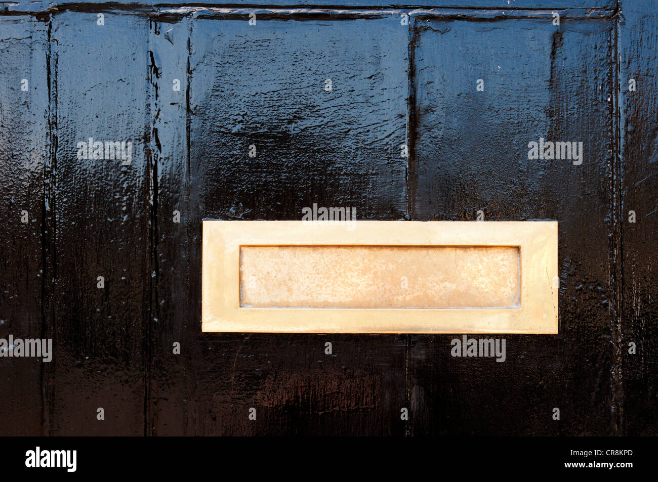 A gold metal letterbox on a black painted door Stock Photo - Alamy