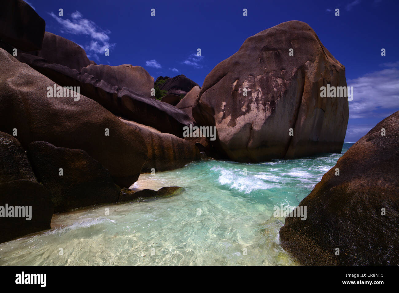 Clear ocean water washes in among weathered shore rocks worn smooth ...