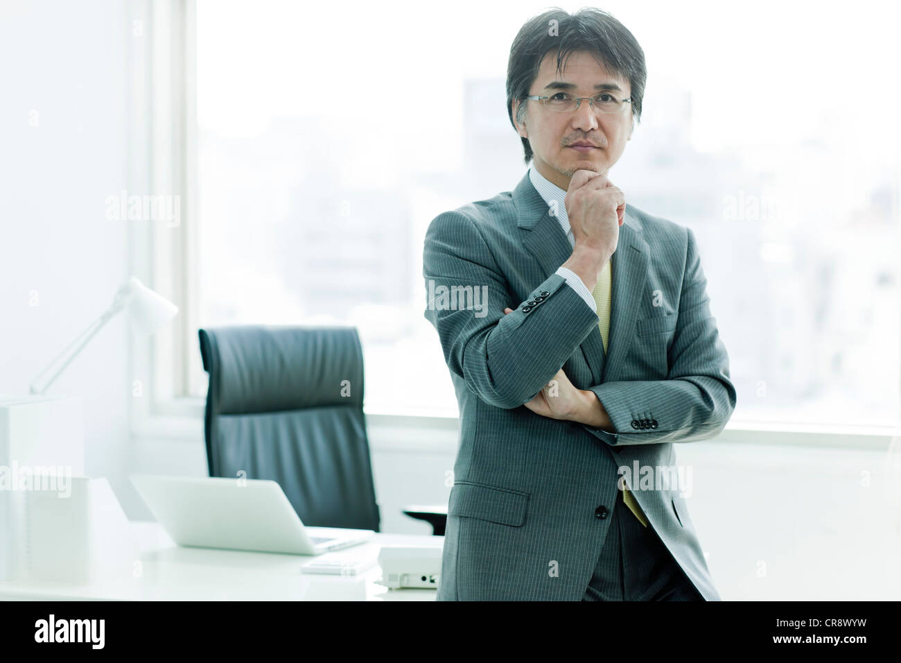 Businessman Sat On Desk, Thinking Stock Photo - Alamy