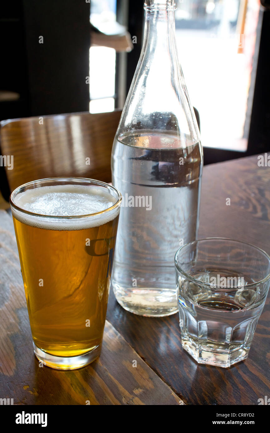 A pint of beer with a glass and a bottle of water in a bar Stock Photo ...