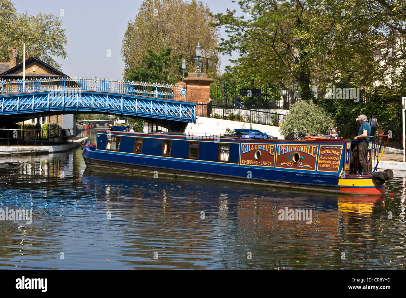 Barge traveling under a blue bridge on the Grand Union Canal London ...