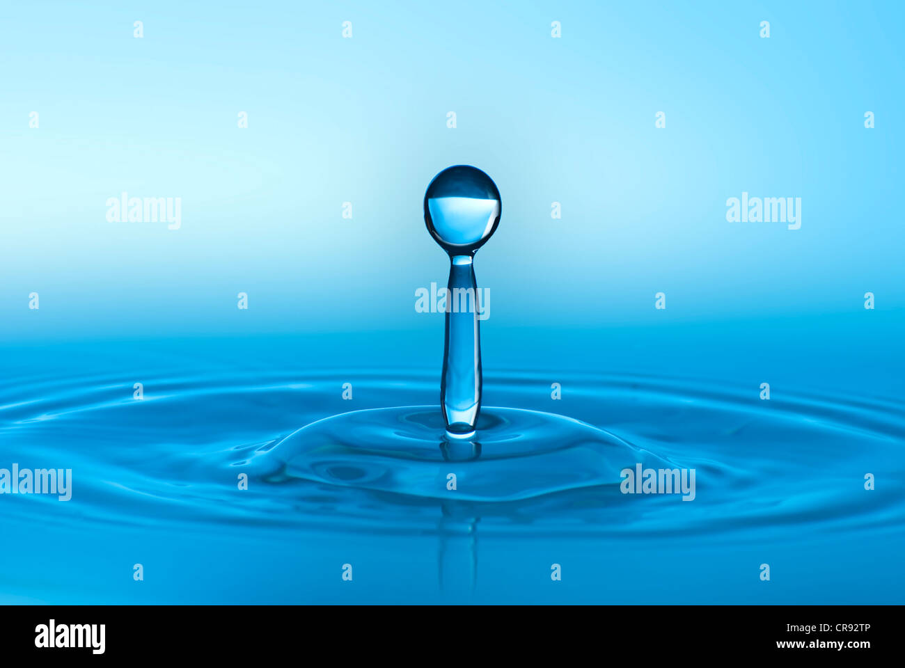 Clean blue drop of water splashing in clear water. Abstract blue ...