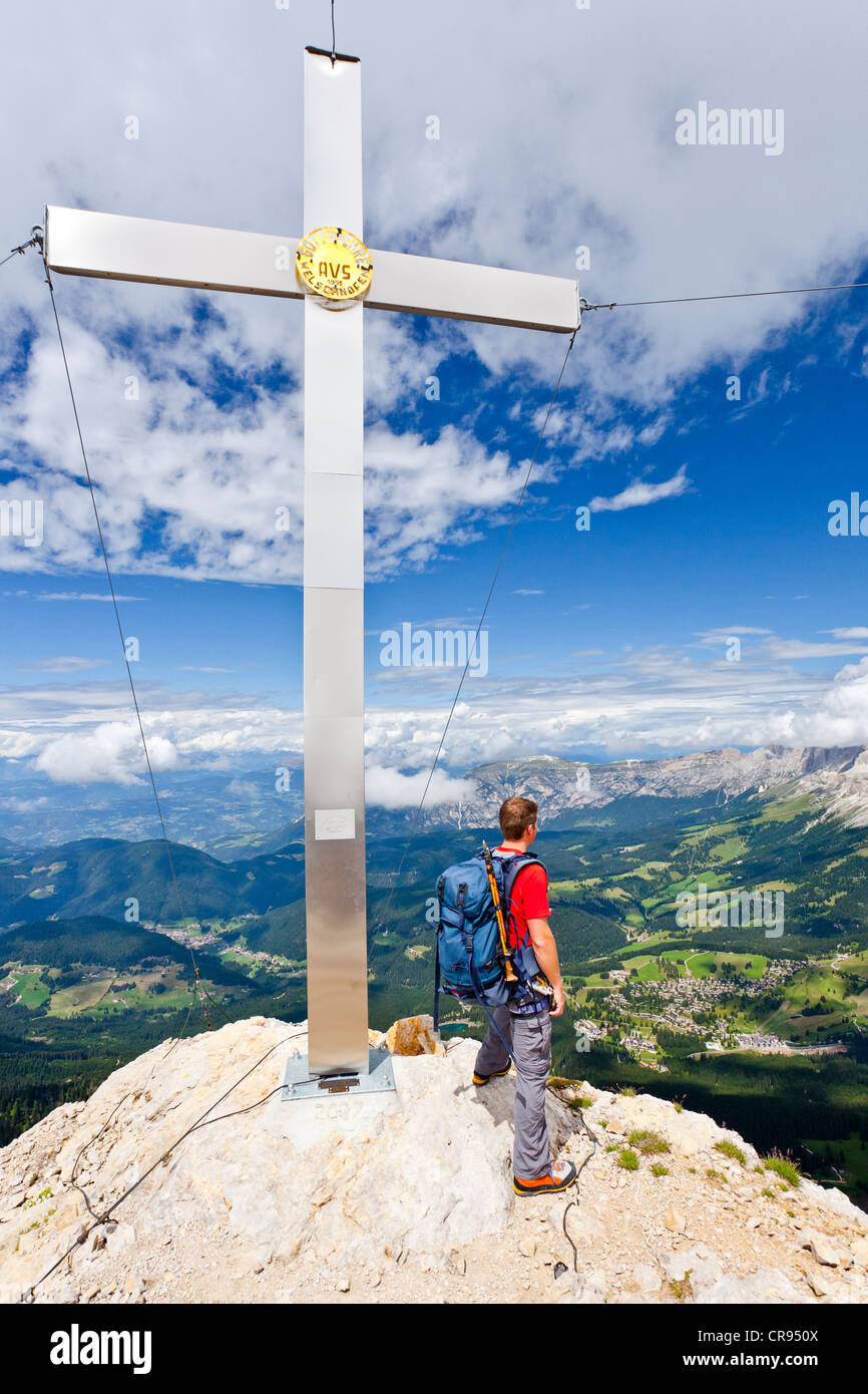 Mountain climber at the summit cross on the Latemar Crossing climbing ...