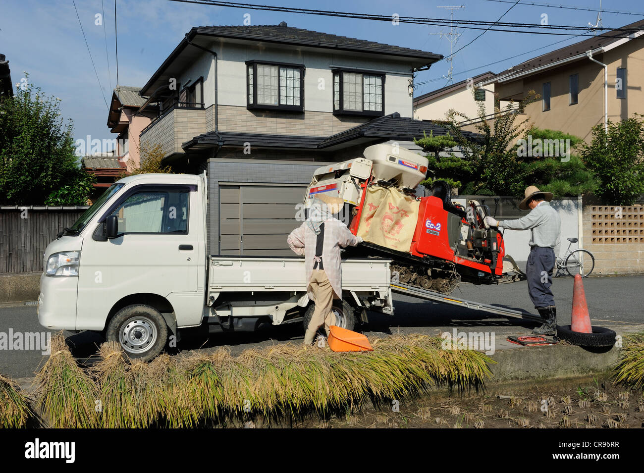 Rice farmer loading his combine harvester on a small truck, Iwakura ...