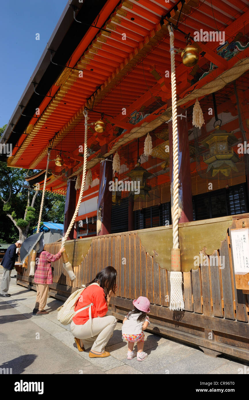Japanese woman with a child in front of the Haiden Hall pulling on the ...