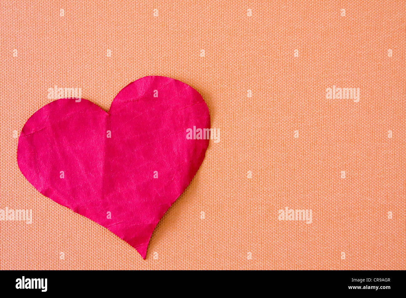 pink paper heart on a orange background Stock Photo - Alamy