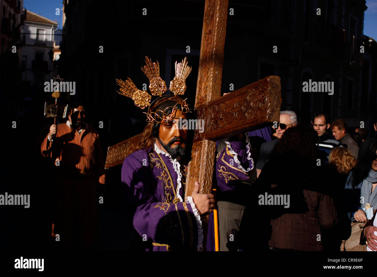 A masked man dressed as Jesus Christ carries a cross during an Easter ...