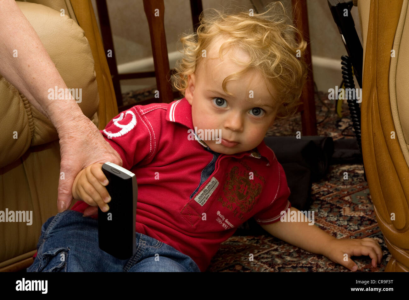 unhappy looking toddler on floor remote control Stock Photo - Alamy
