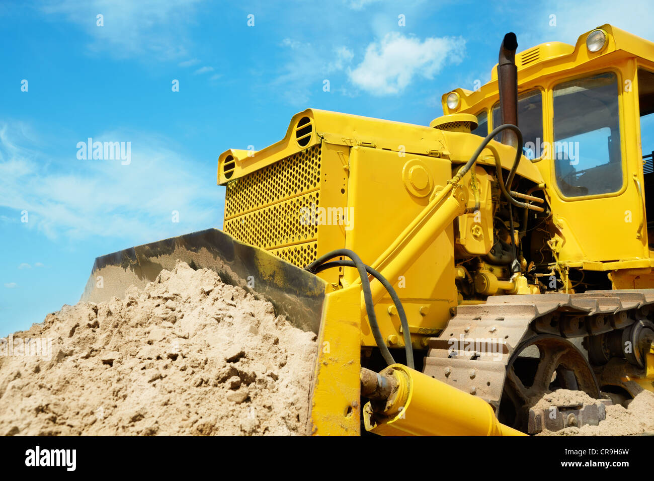 Bulldozer at work on blue sky background Stock Photo - Alamy
