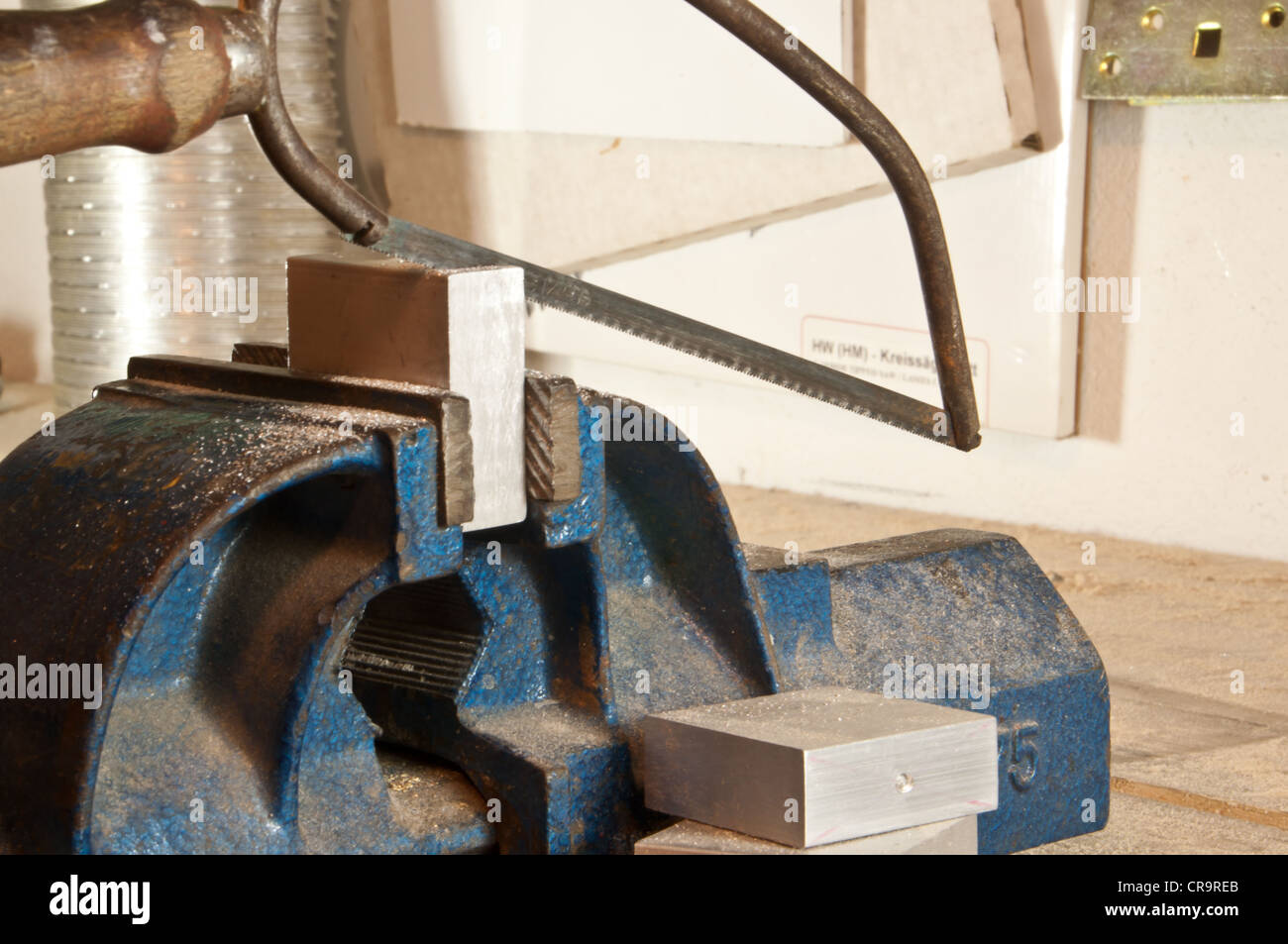 Sawing in a block of metal in a vice on a wooden workbench Stock Photo ...