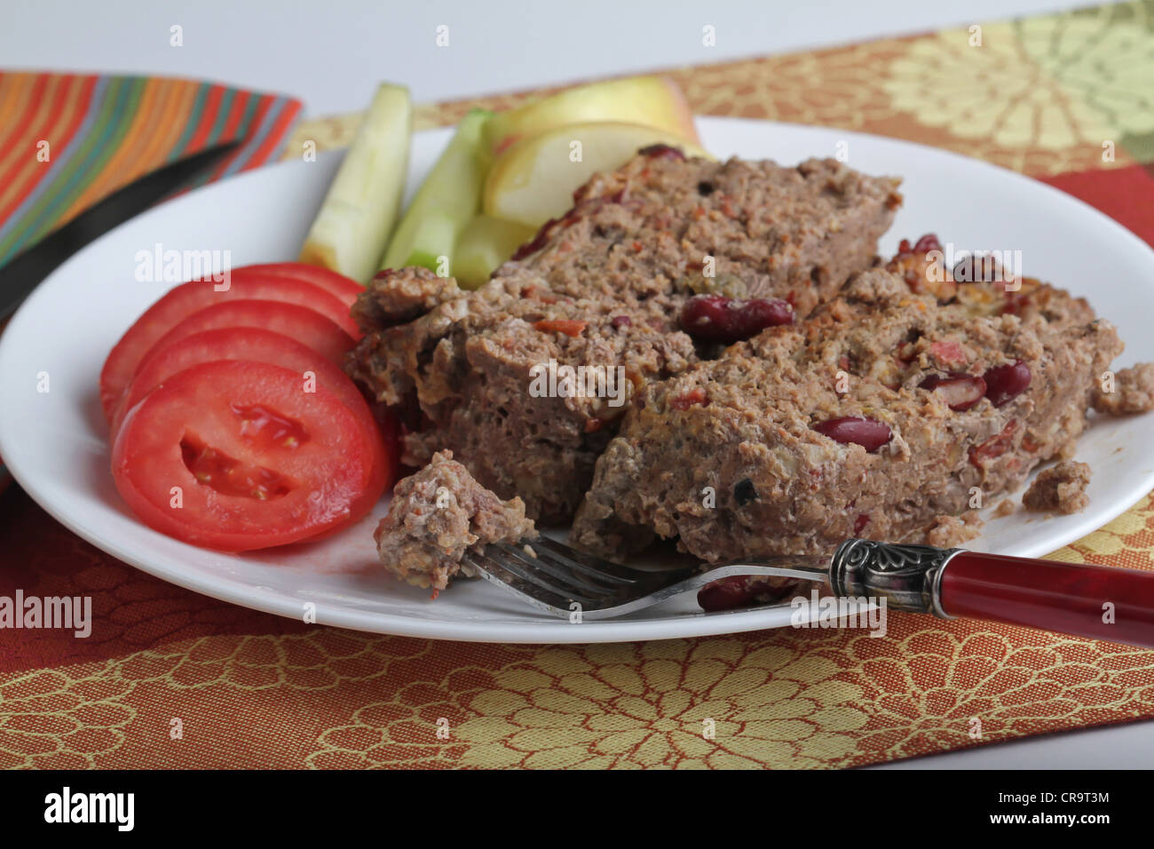 A dinner plate of homemade meatloaf with sides of Roma tomatoes and ...