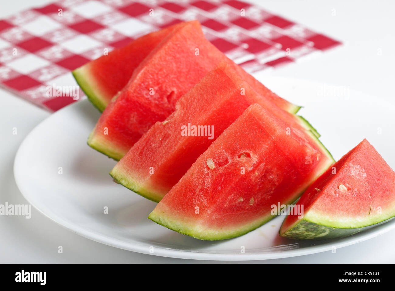 A plate of seedless watermelon slices on a white plate with red and ...