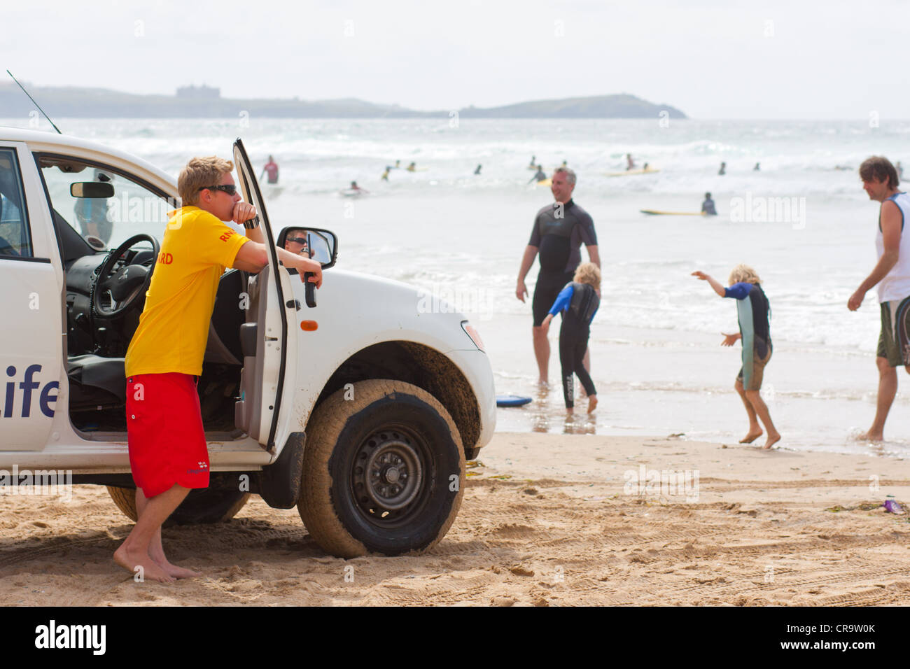 A lifeguard standing by his van whilst watching the beach to keep it ...