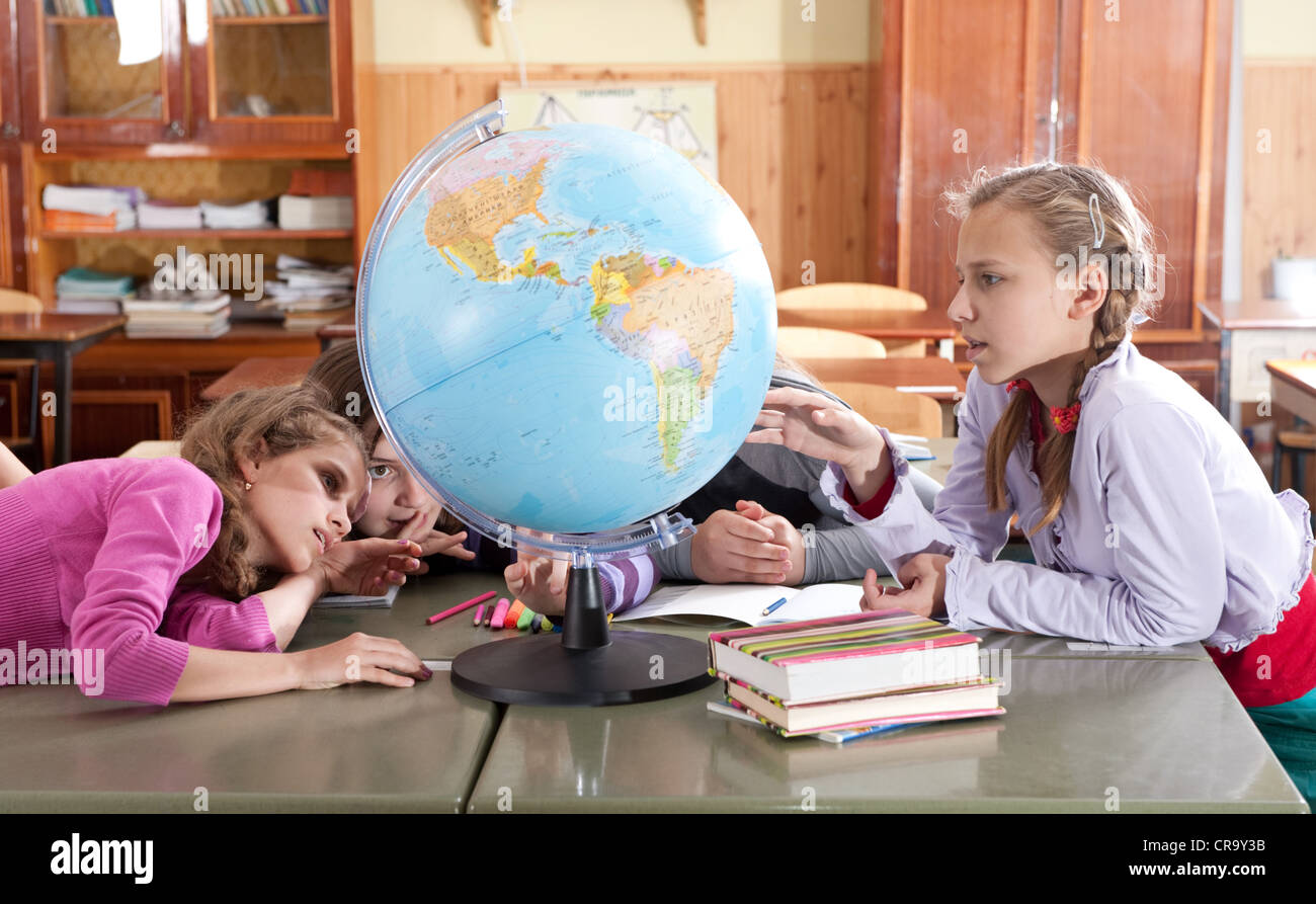 Schoolchildren are exploring globe in classroom during lesson Stock ...