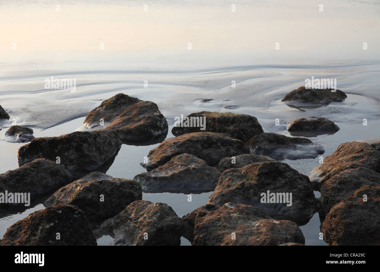It' a photo of rocks on the beach near the ocean or the sea. It' the ...
