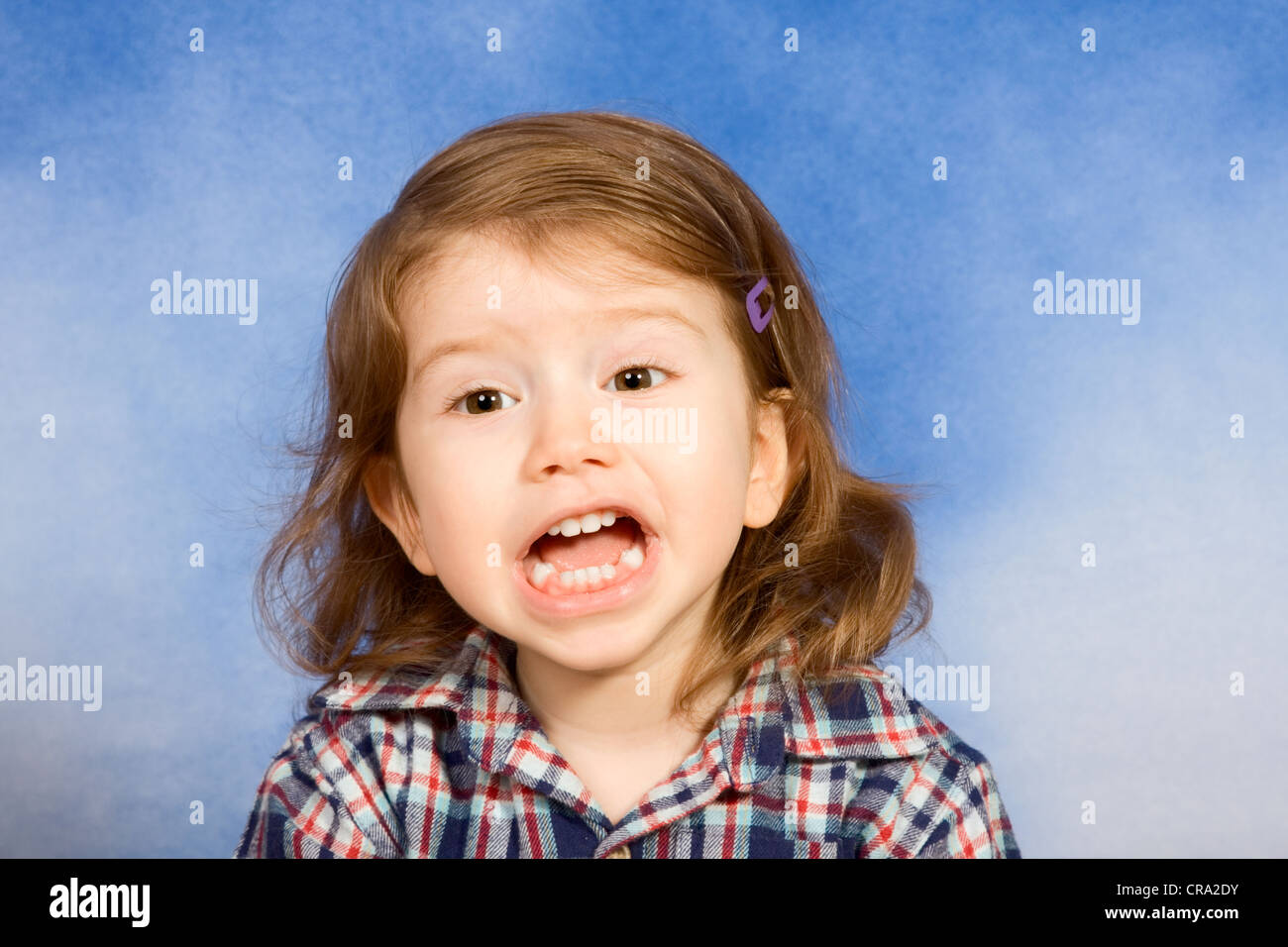 Portrait of emotionally distressed kid with open mouth and long hair ...