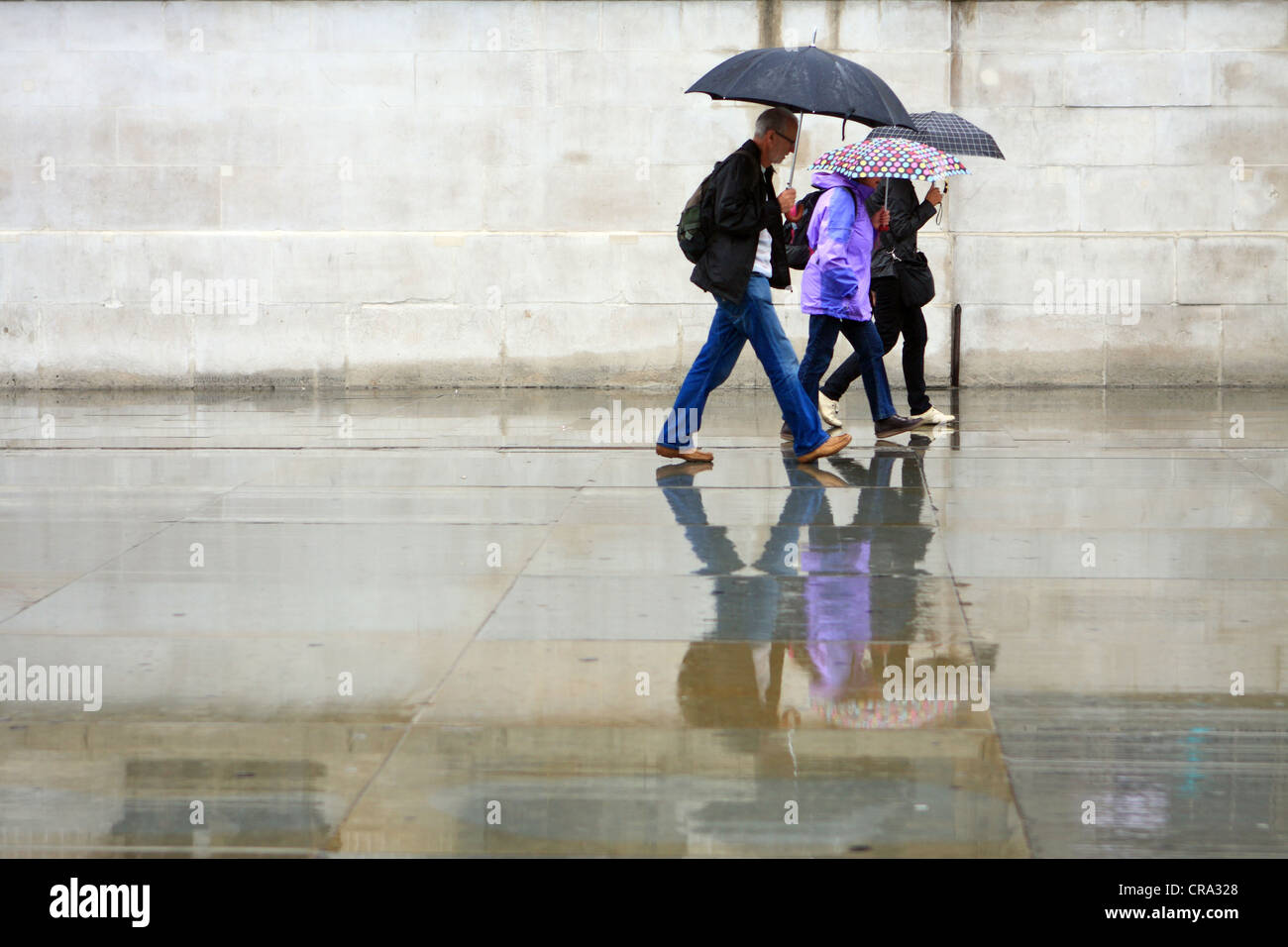 people walking passed a plain wall in the rain Stock Photo - Alamy