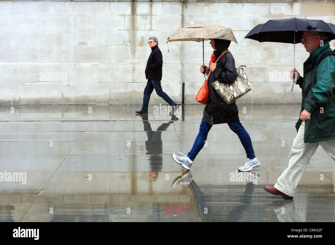 people walking passed a plain wall in the rain Stock Photo - Alamy