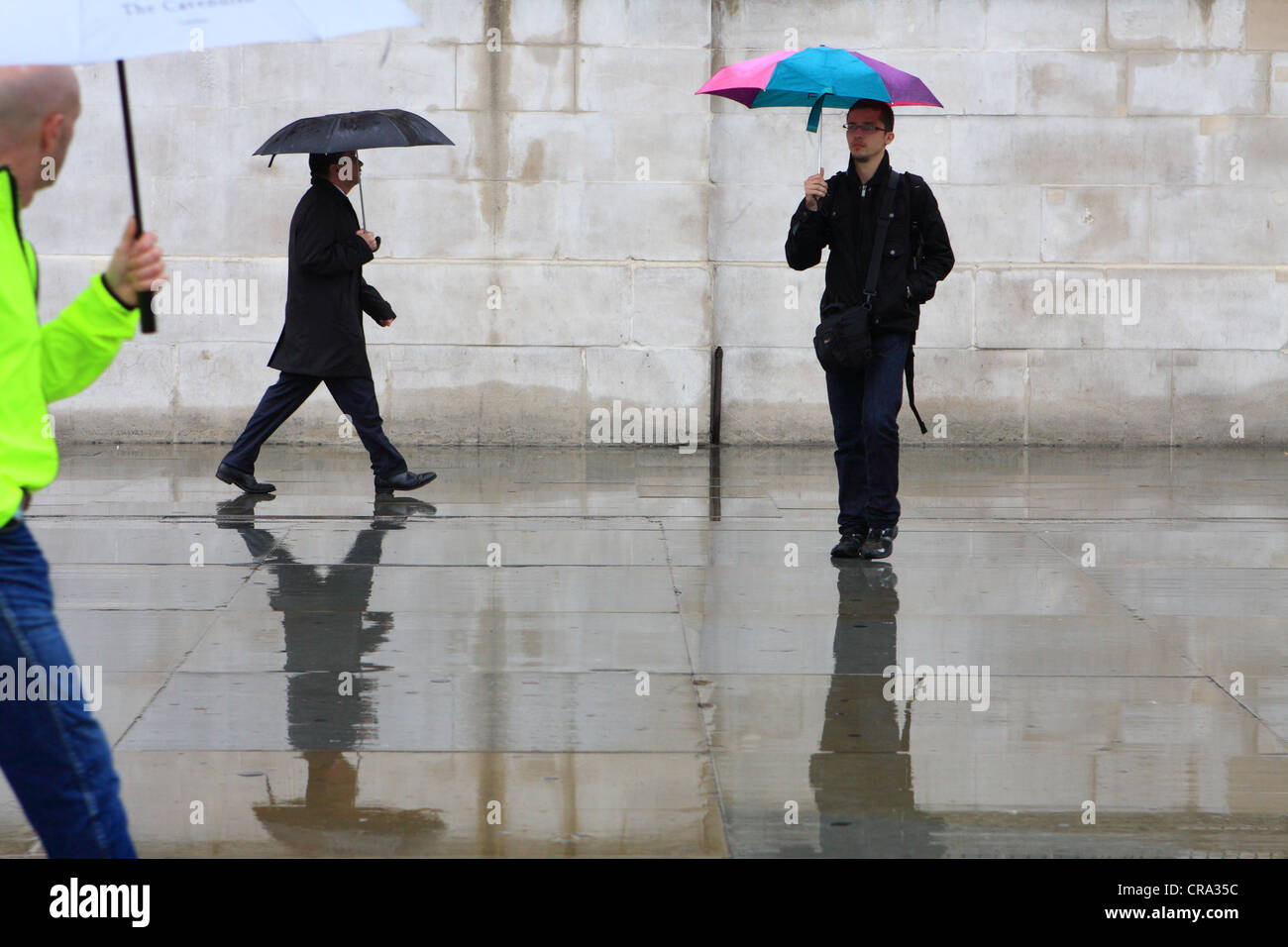 people walking passed a plain wall in the rain Stock Photo - Alamy