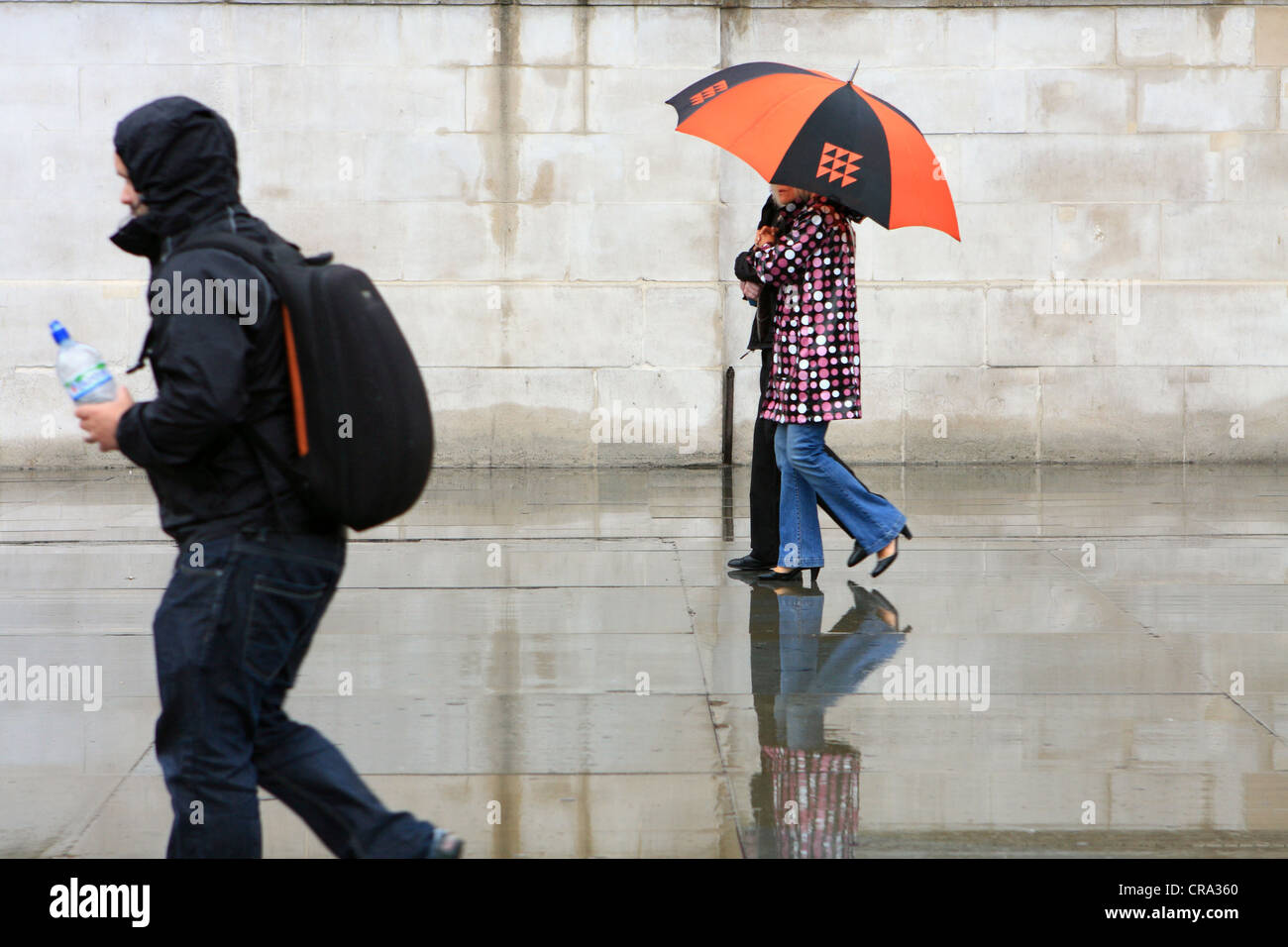 people walking passed a plain wall in the rain Stock Photo - Alamy