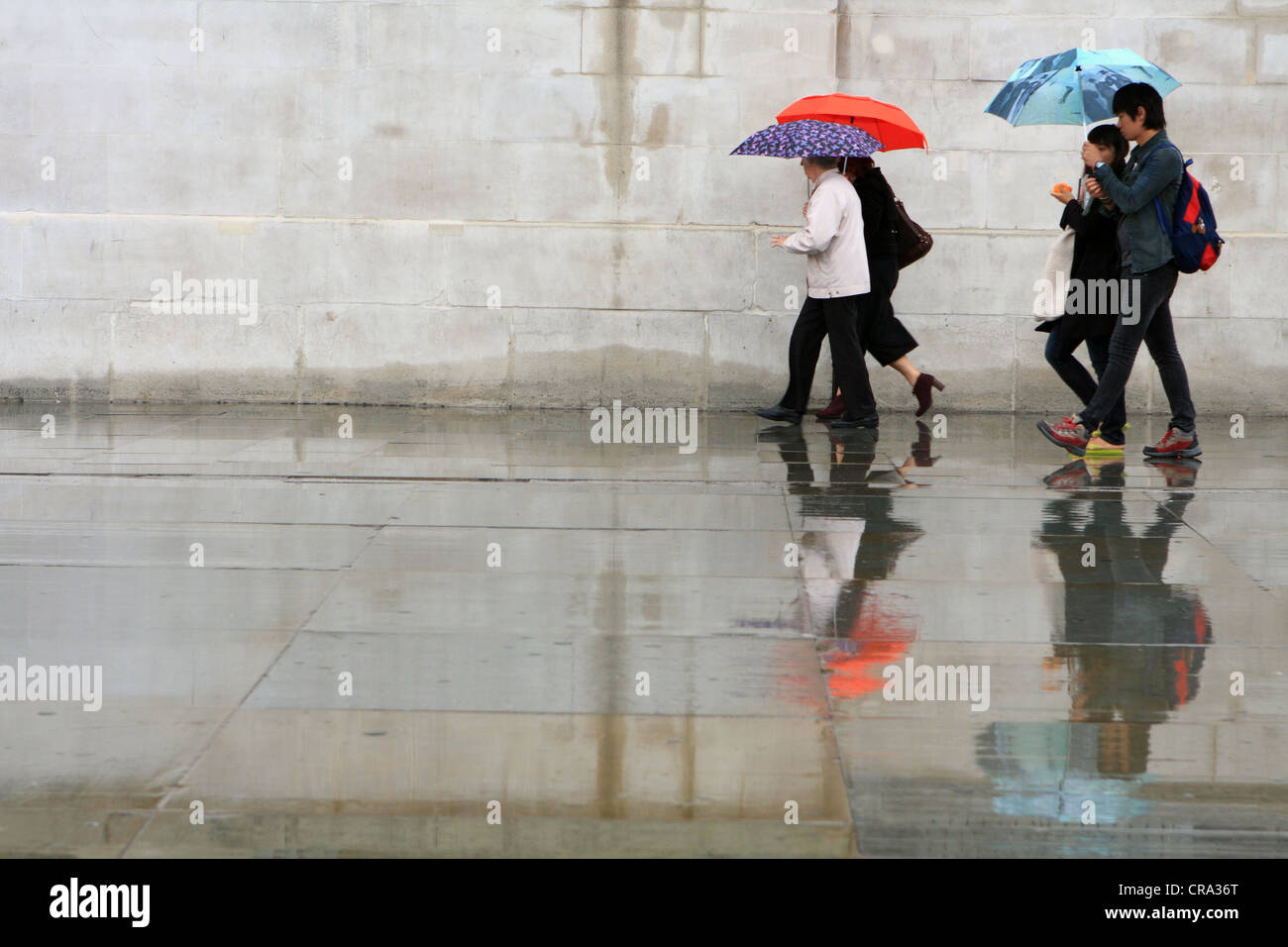 people walking passed a plain wall in the rain Stock Photo - Alamy