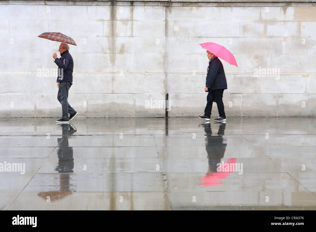 people walking passed a plain wall in the rain Stock Photo - Alamy
