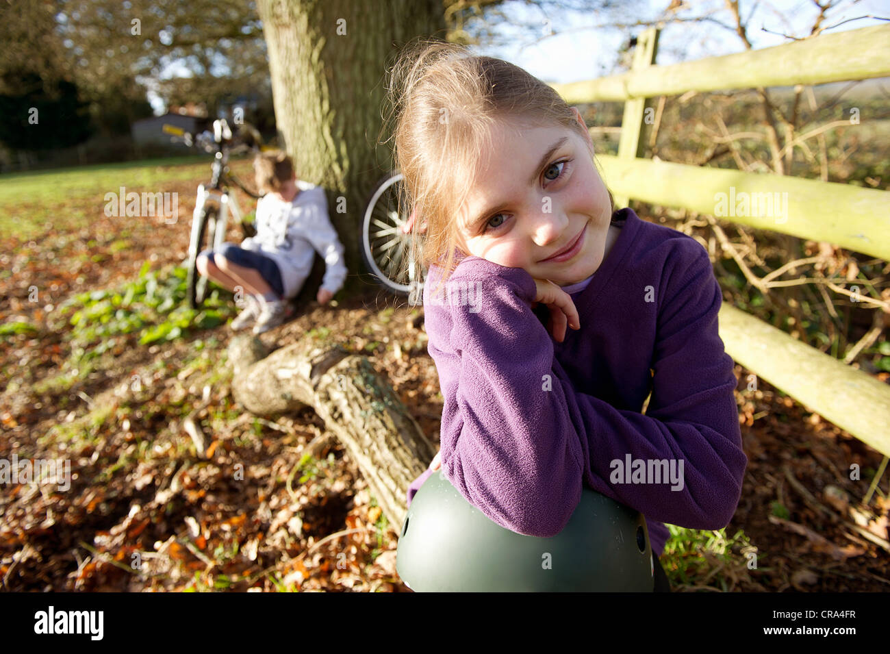 Girl sitting on log in meadow Stock Photo - Alamy