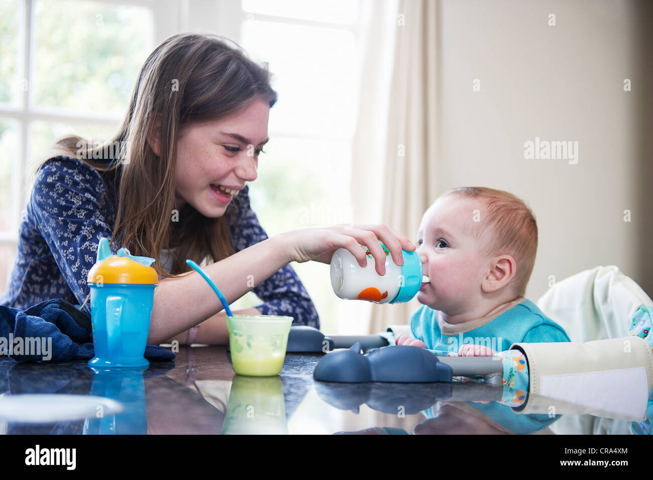 Girl feeding baby brother at table Stock Photo - Alamy