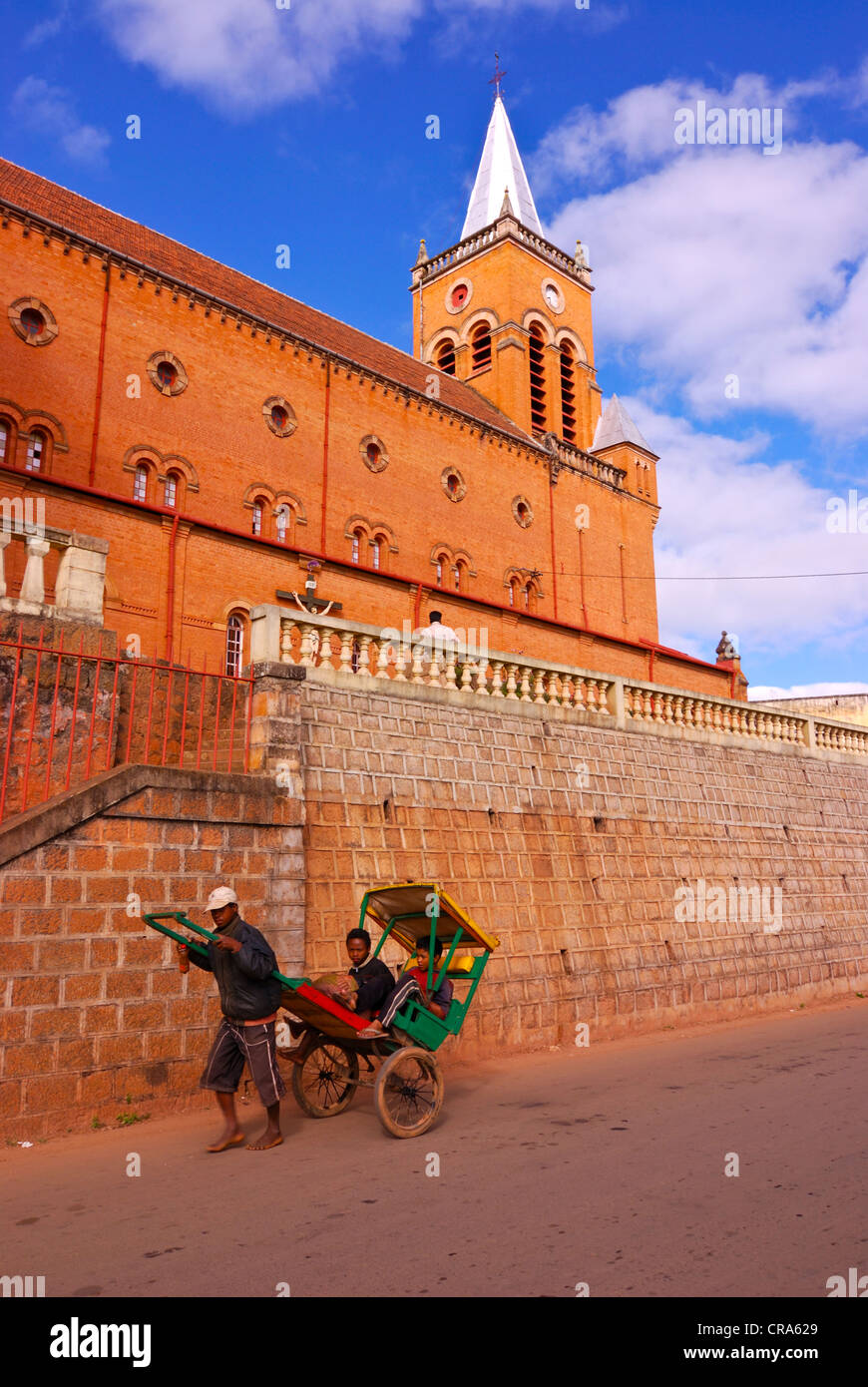 Man transporting a passenger with his rickshaw in front of a brick ...