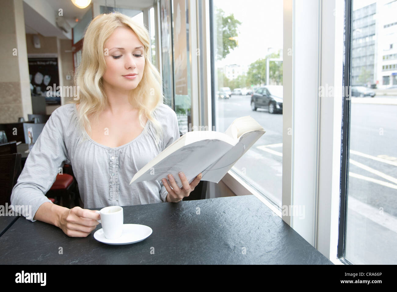 Woman reading book in cafe Stock Photo - Alamy