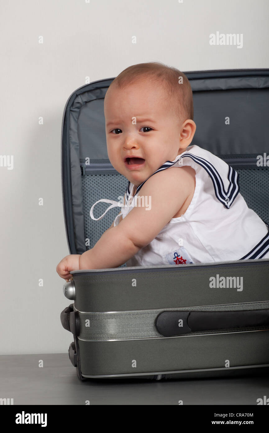 Portrait of a cute little baby crying in a suitcase Stock Photo - Alamy