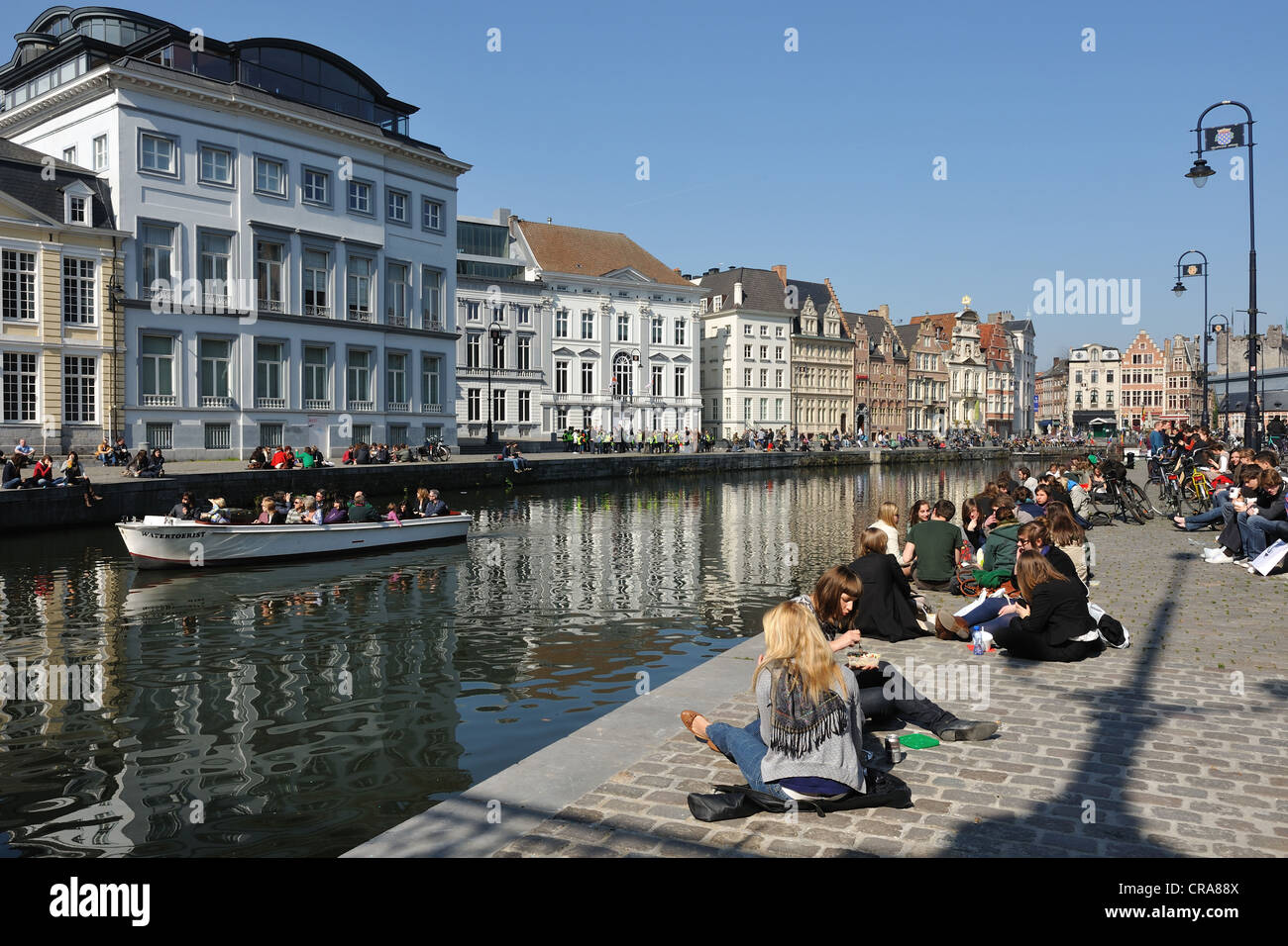 People sitting along the banks of the Lys river on a sunny day, Ghent ...