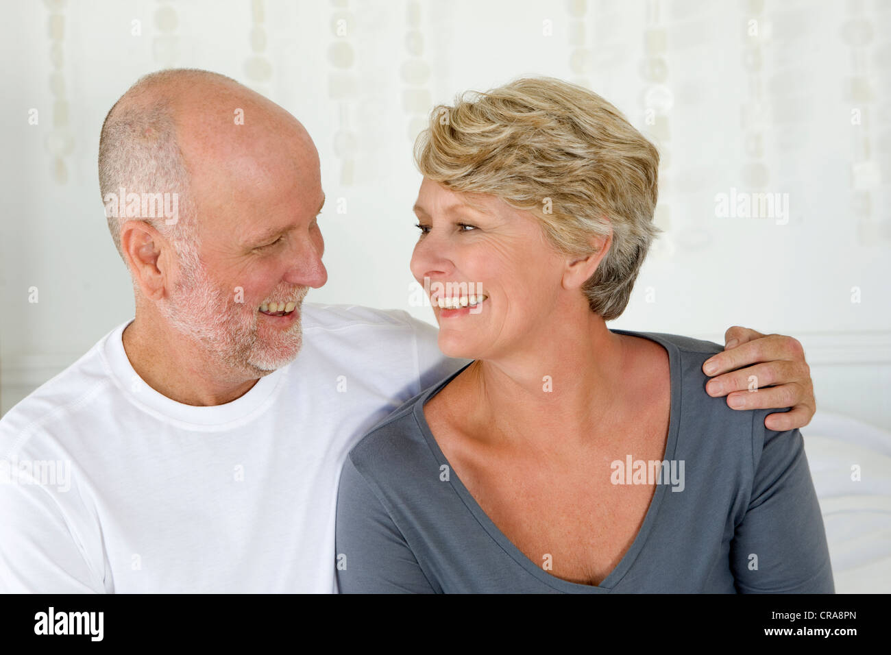 Smiling older couple sitting on bed Stock Photo - Alamy