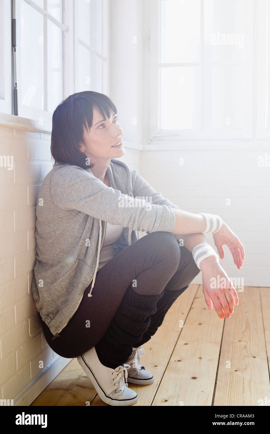 Woman resting against wall in studio Stock Photo - Alamy
