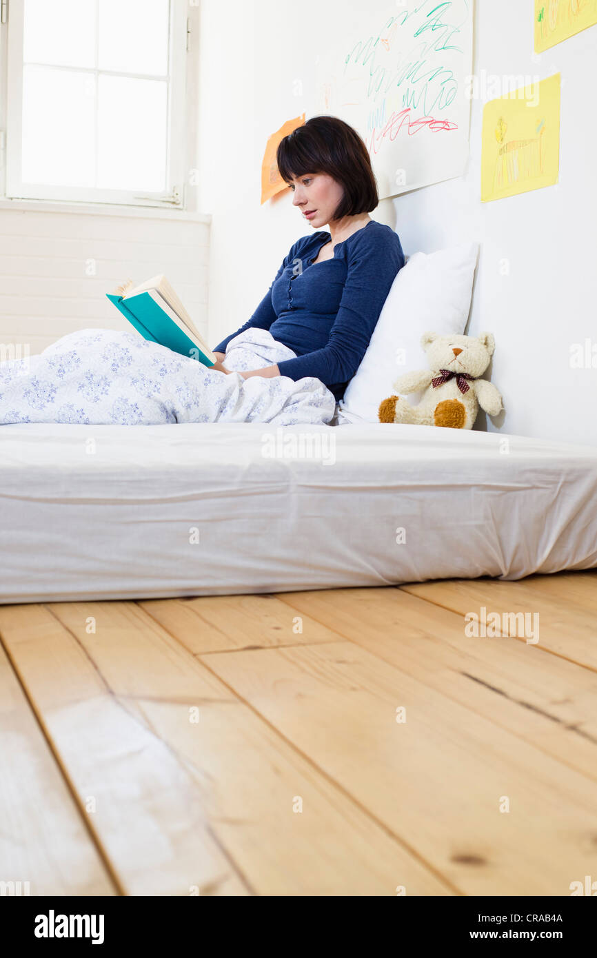 Woman reading book in bed Stock Photo - Alamy