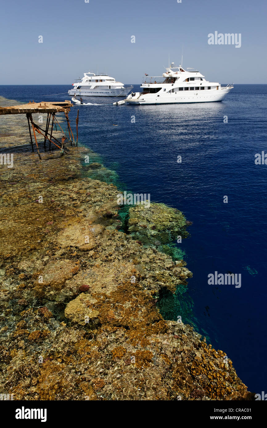 Dive ships anchor off the jetty in front of the reef top, Daedalus Reef ...