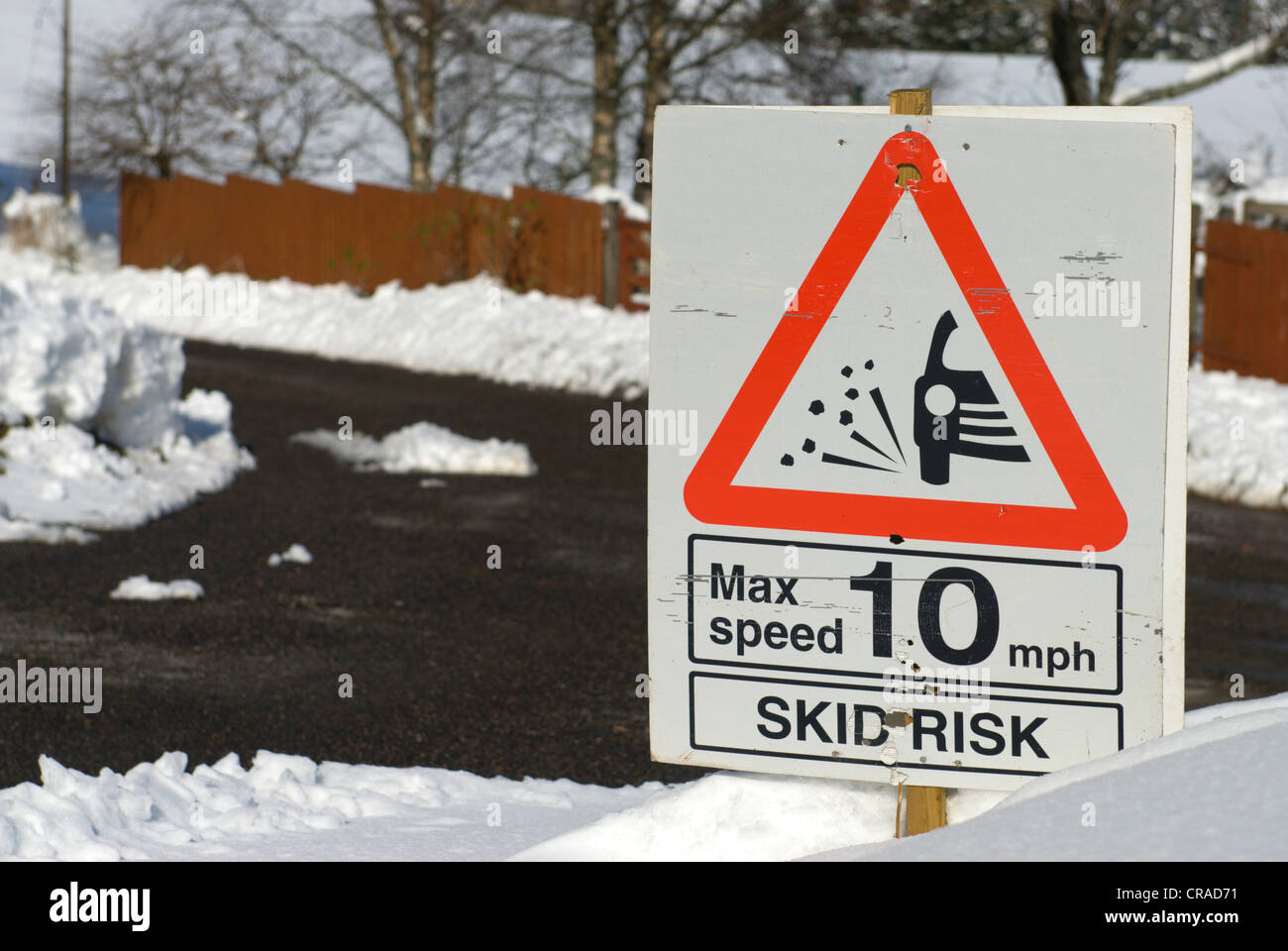 Warning sign indicates a skid risk on a snowy rural Scottish road Stock ...