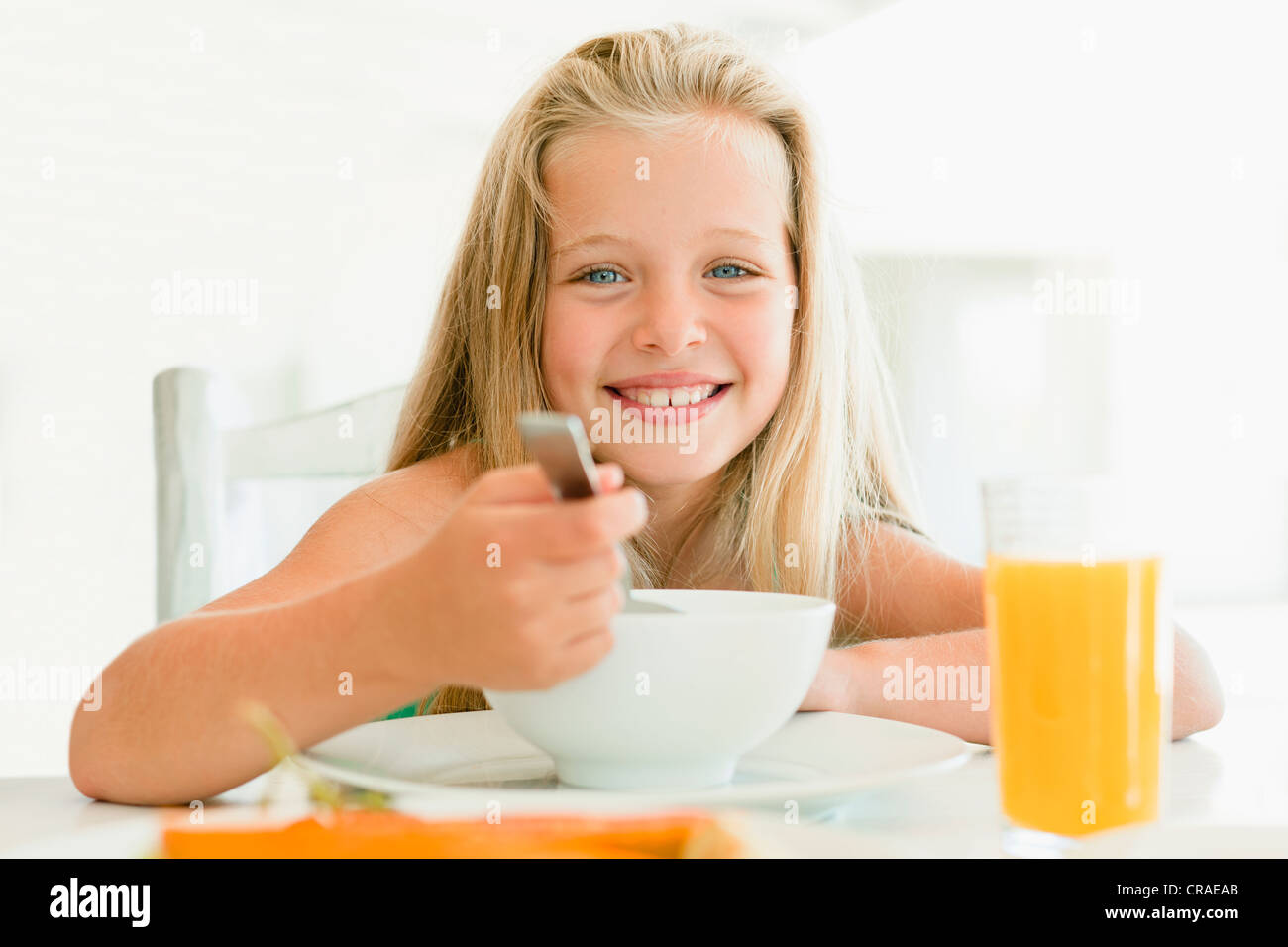 Girl eating cereal at breakfast table Stock Photo - Alamy