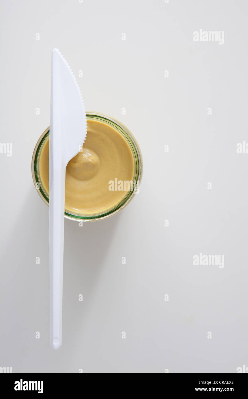 Mustard glass with a plastic knife Stock Photo - Alamy