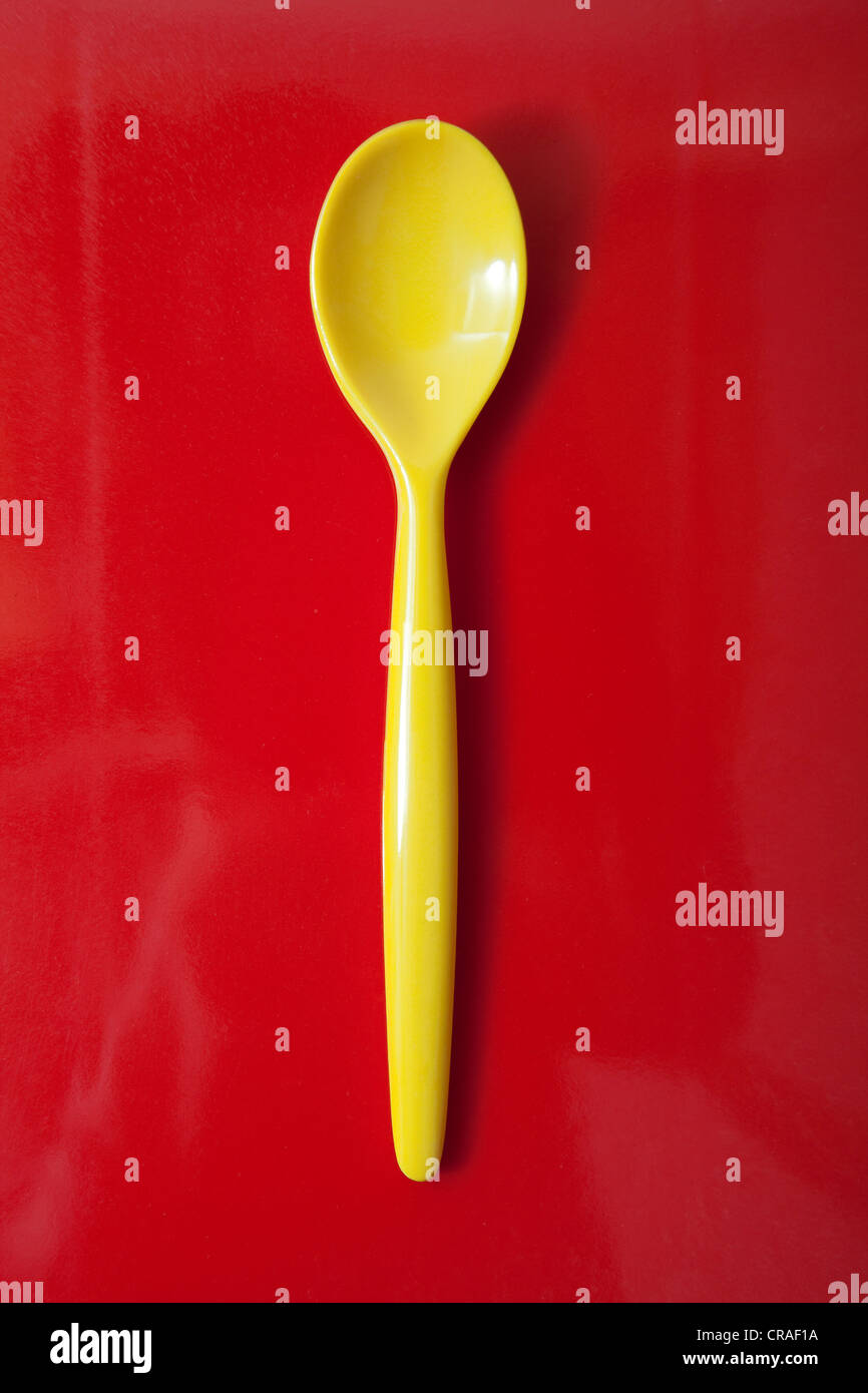 Yellow plastic spoon, egg spoon, on red Stock Photo - Alamy