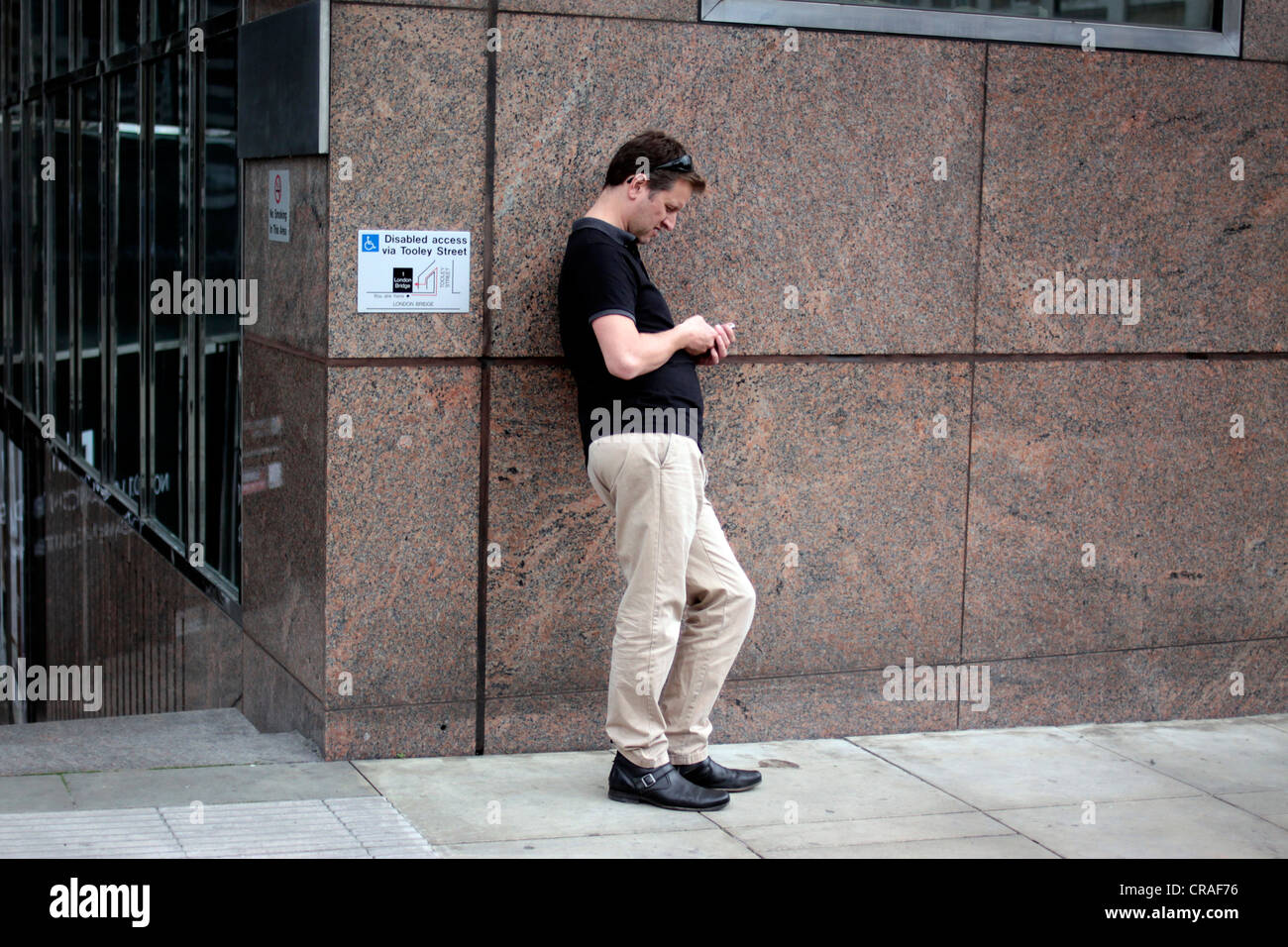 Man checking his mobile phone on a street in London Stock Photo - Alamy