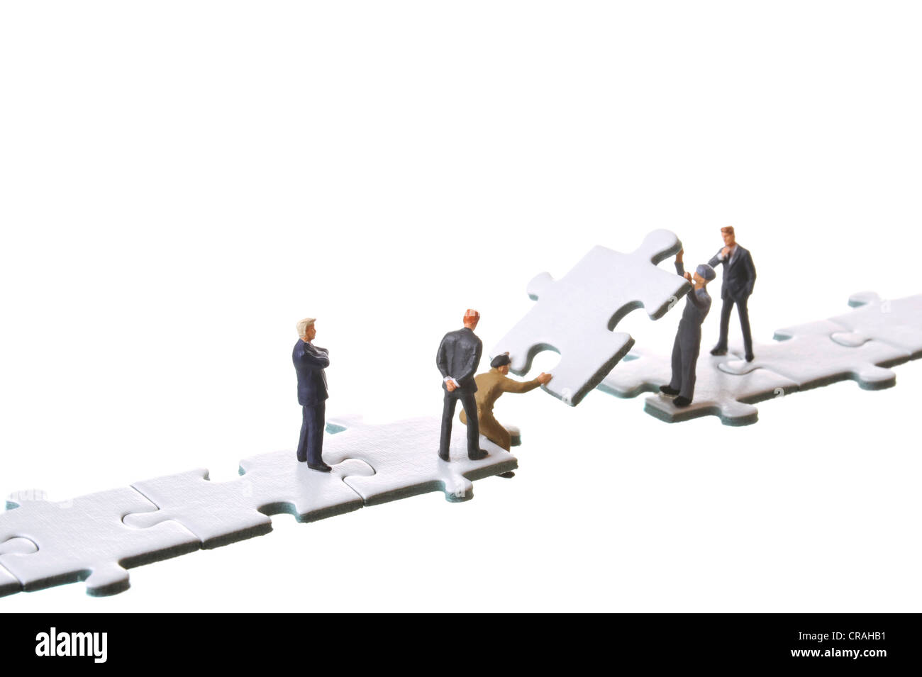 Figures of businessmen building a bridge with puzzle pieces, symbolic ...