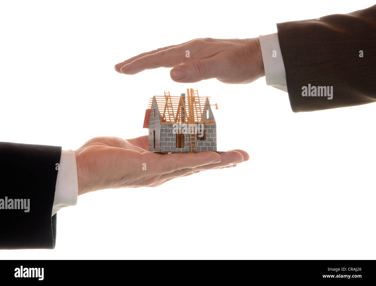 Man's hand holding a model of a house while another man's hand is held ...