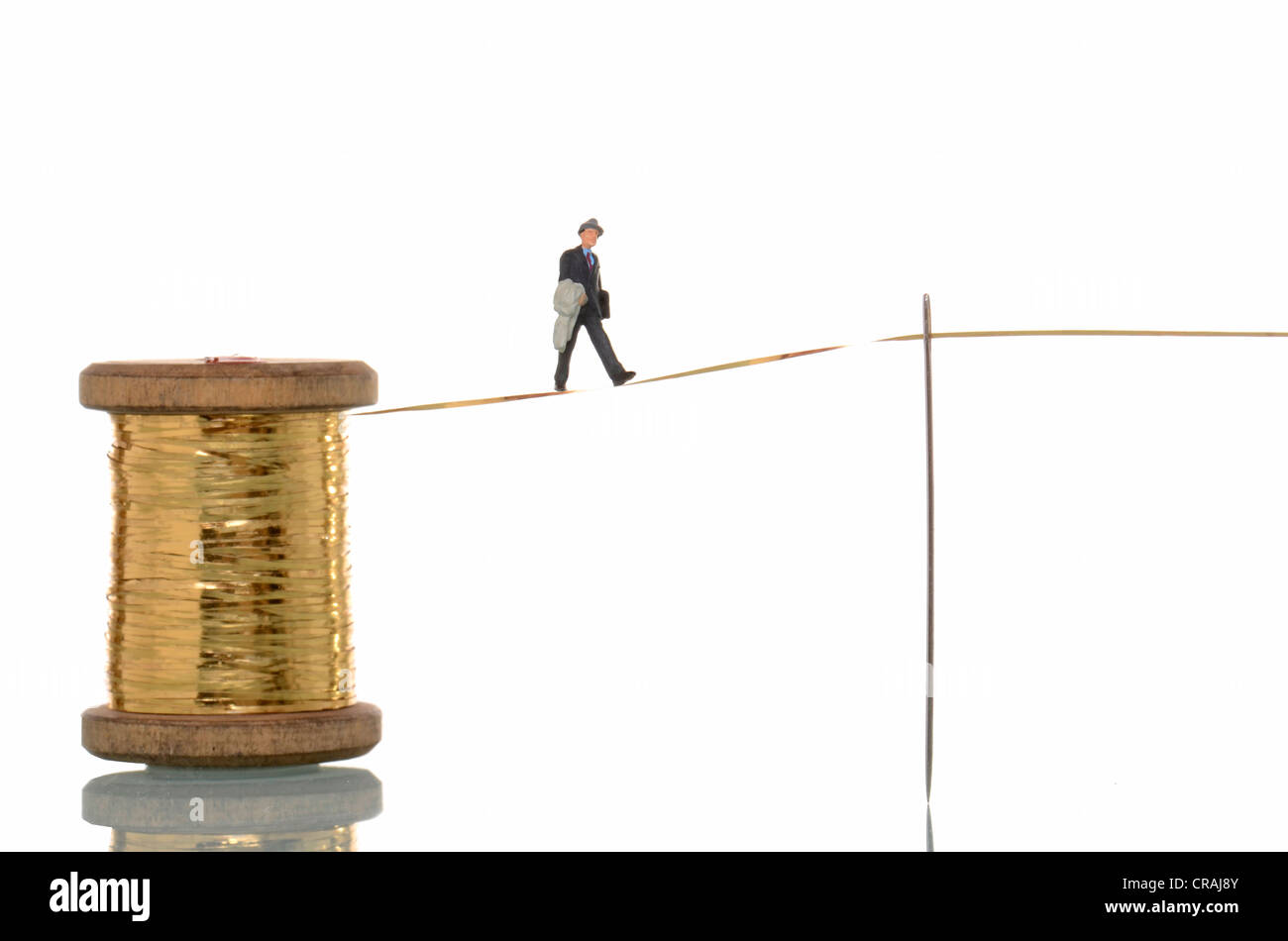 Business man figure balancing on golden thread, symbolic image for the ...