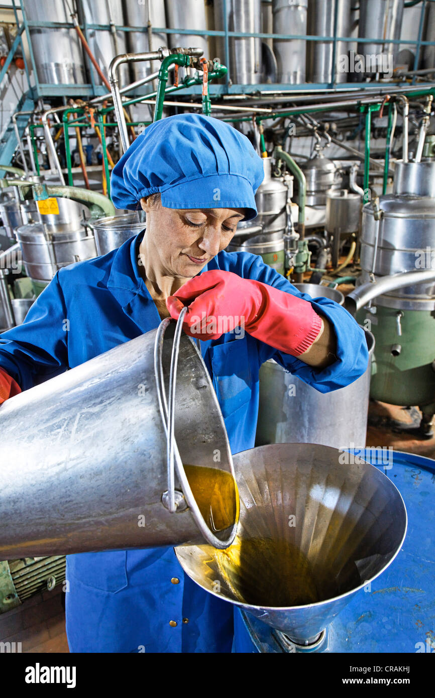 Freshly pressed lemon oil being poured from a bucket into a barrel by a ...