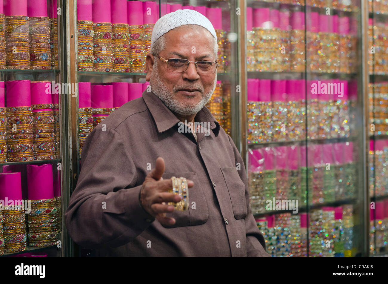 Merchant holding some of Hyderabad's famous glass armlets, bazaar, the ...