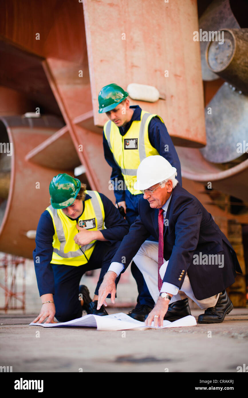 Workers reading blueprints on dry dock Stock Photo - Alamy