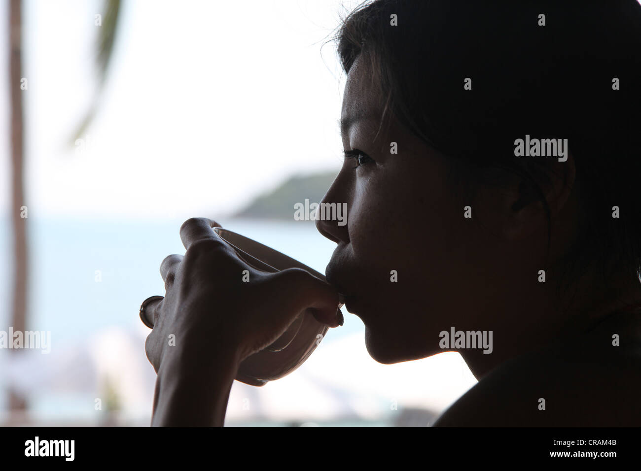 A Chinese woman is drinking tea in a bowl near the beach in a resort ...