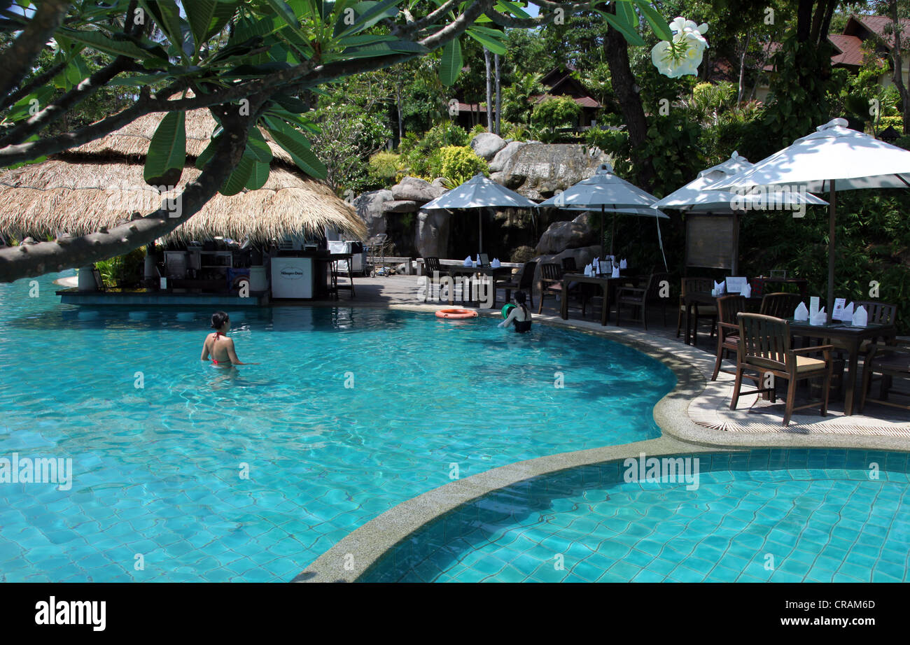 It's a photo of a resort hotel with a swimming pool. It's sunny day and ...